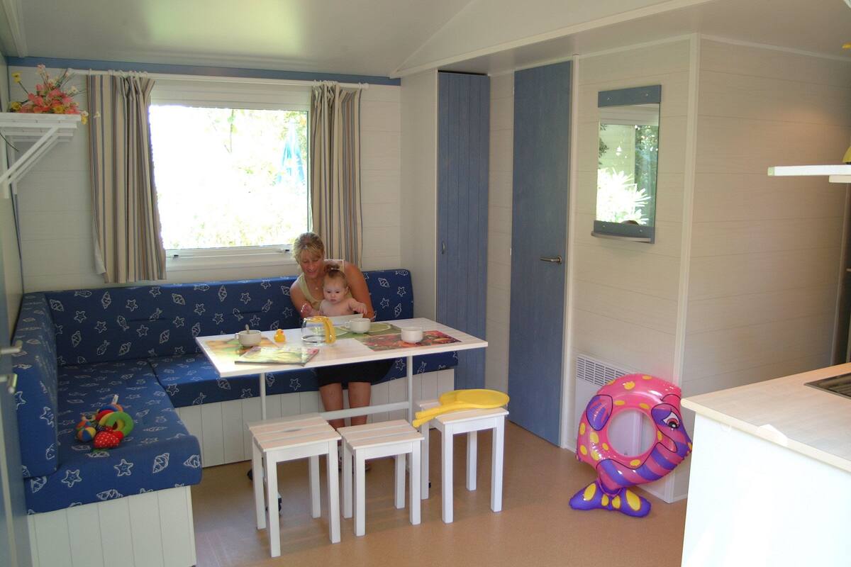 Um quarto com um sofá azul, uma mesinha e uma criança brincando com brinquedos.