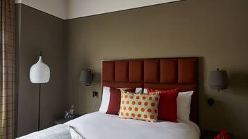 Quarto de hotel com uma cama grande, cabeceira, duas luminárias de apoio, mesa de cabeceira e telefone.