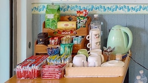 Uma cozinha compacta com cafeteira, saquinhos de chá e diversos alimentos.