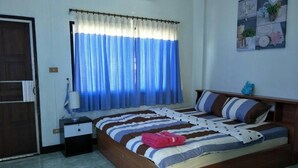 Quarto com cama de madeira, roupa de cama listrada, mesa de cabeceira, abajur e ar condicionado fixado na parede.