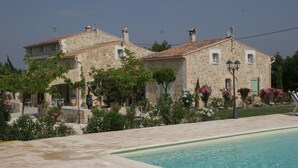 Um edifício de pedra com piscina, rodeado por vegetação e flores.