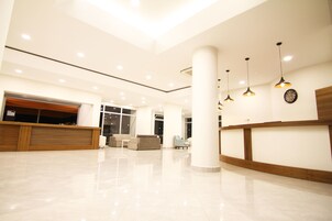Um hall amplo com balcão de recepção, área de estar e luminárias modernas.