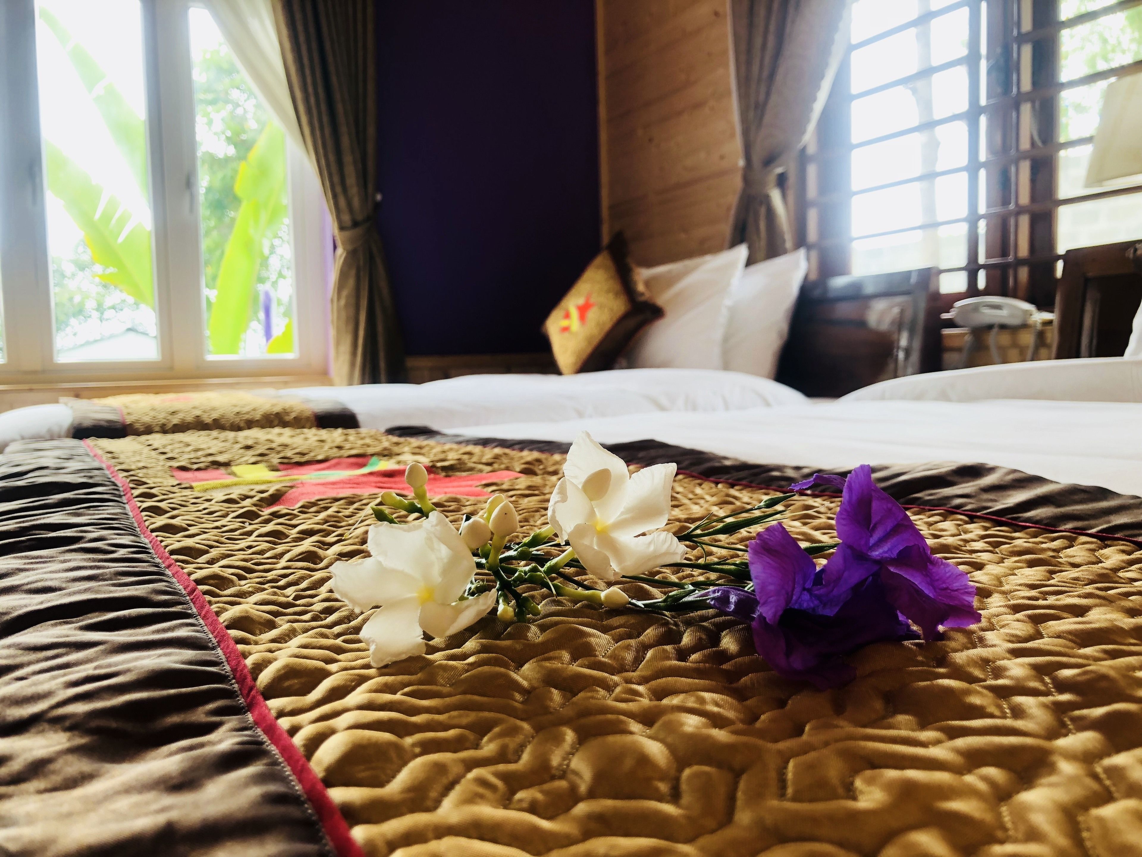 Quarto de hotel com uma cama, janela com cortinas e mesa de cabeceira com telefone.