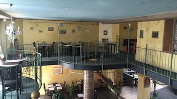 Restaurante em vários níveis, com escadaria central, mesas, cadeiras e um candelabro.