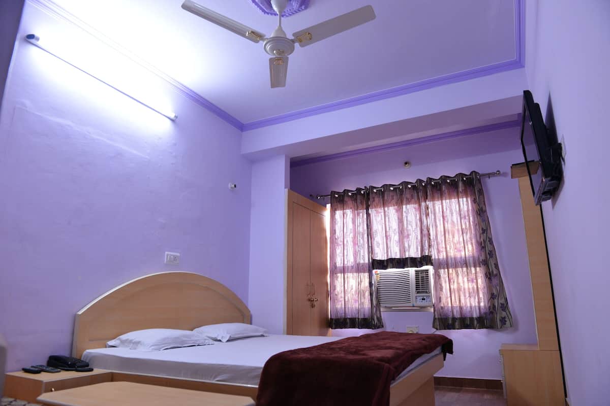 Quarto com cama, ventilador de teto, ar condicionado e televisão na parede.