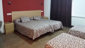 Quarto com cama, mesa de cabeceira, cadeira e janela com cortinas.