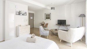 Quarto de hotel moderno com uma cama grande, uma escrivaninha, uma cadeira e uma televisão.