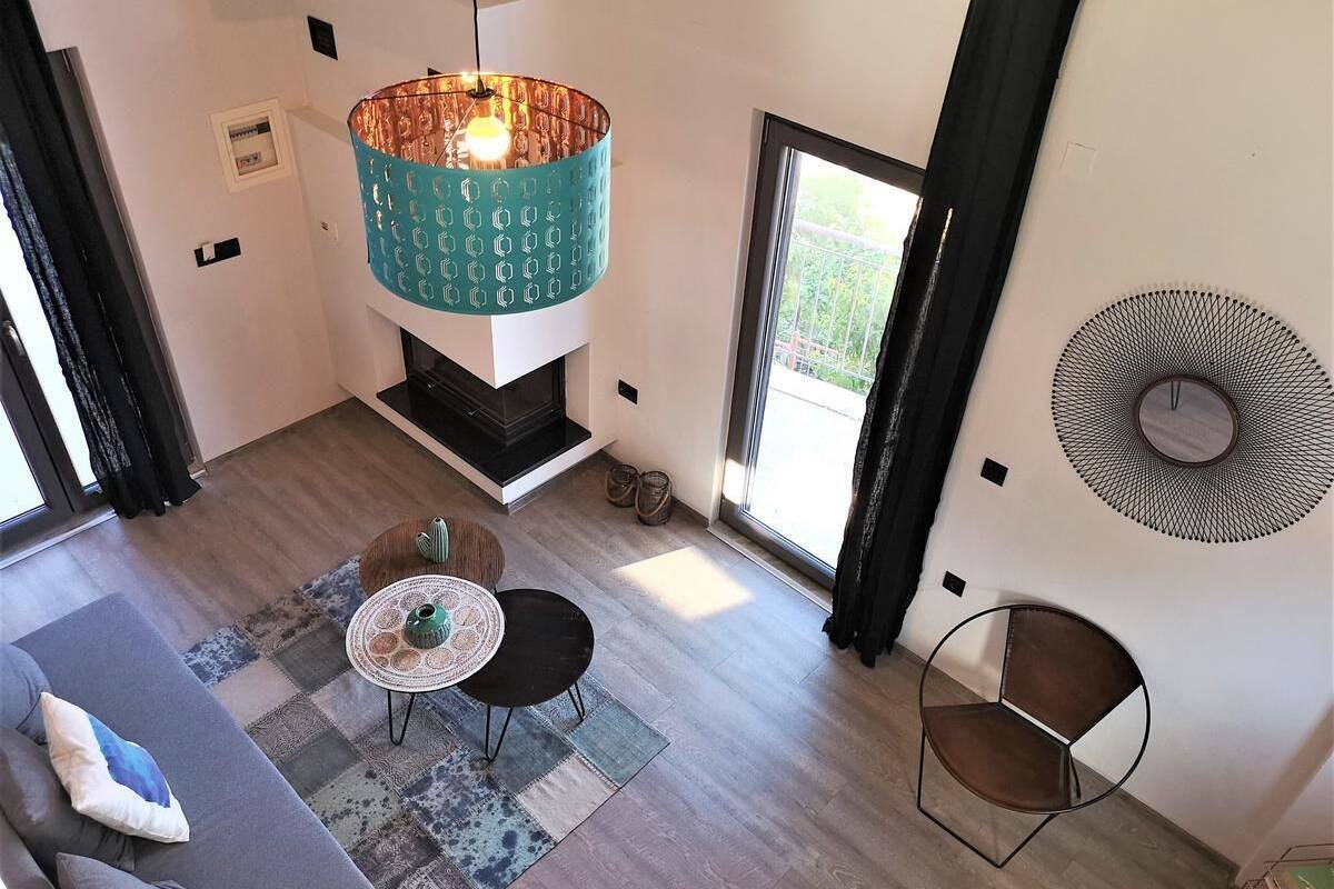 Uma sala de estar moderna com lareira, uma mesa redonda, duas cadeiras, um sofá e uma janela grande.