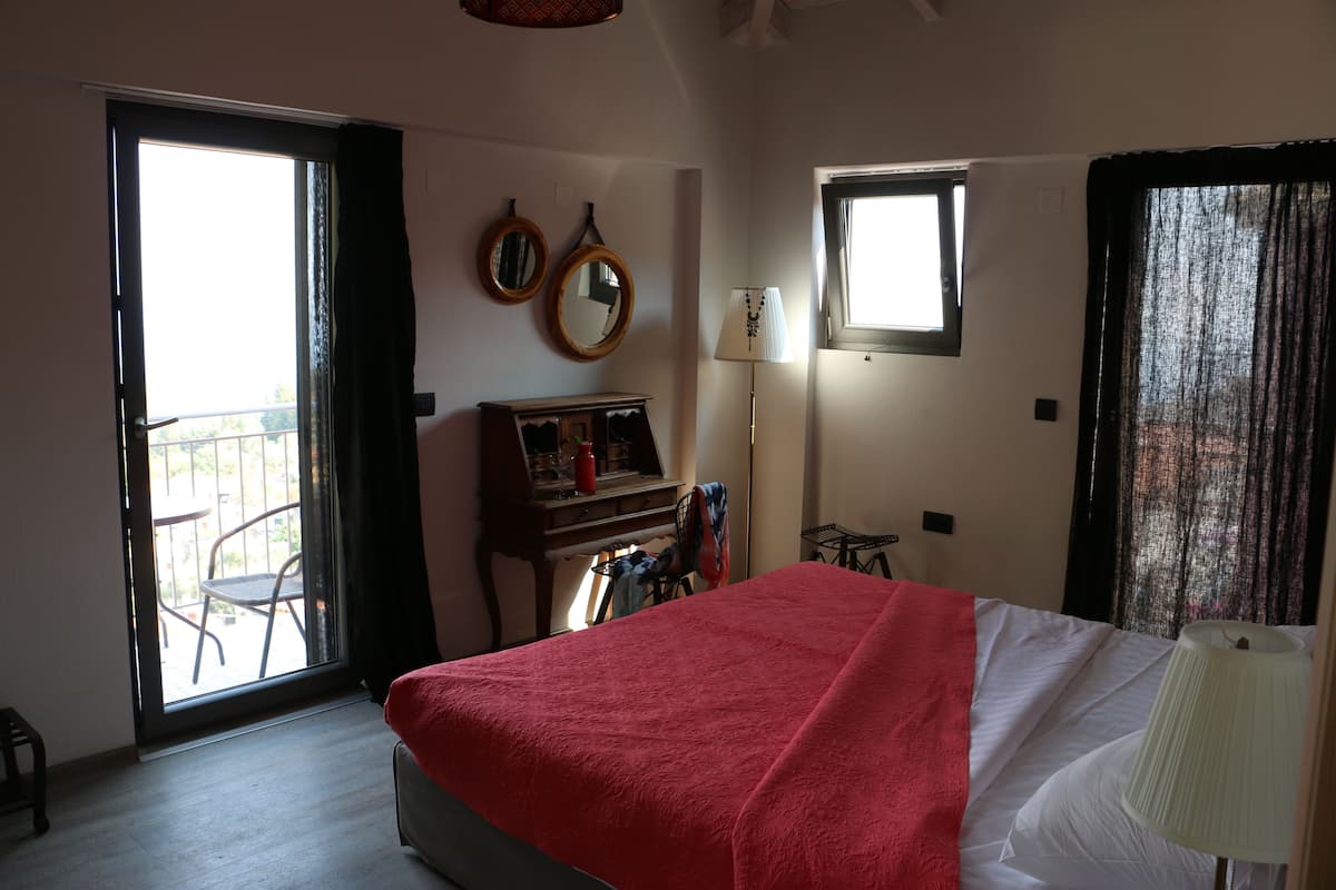 Quarto com cama, escrivaninha, cadeira e janela.