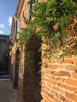 Um edifício de tijolos com uma passagem estreita e um portão de ferro forjado.