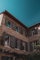 Um edifício de vários andares de tijolo, com janelas com persianas e um canto aparente.