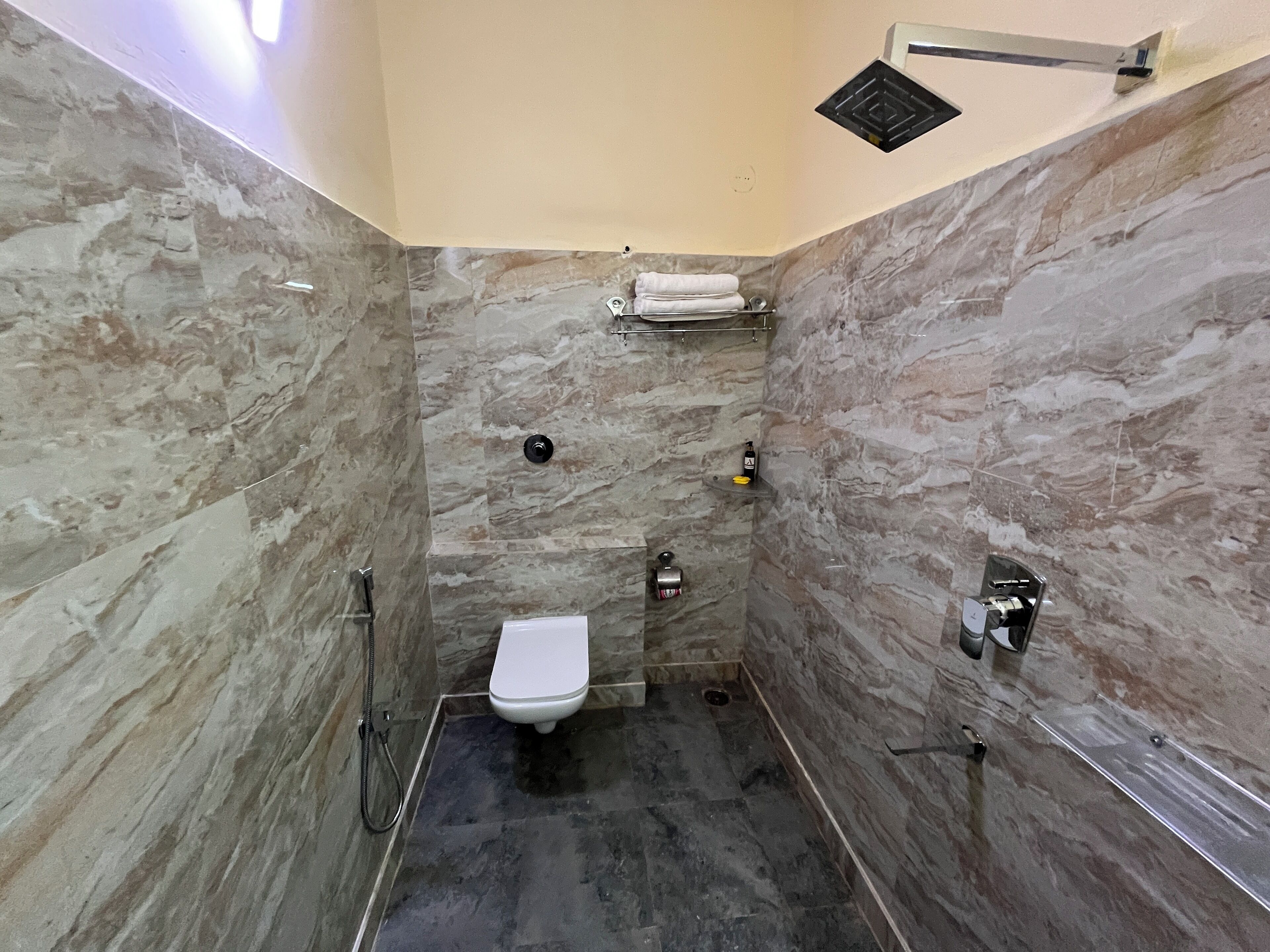 Um banheiro pequeno e moderno com vaso sanitário, chuveiro e porta-toalhas.