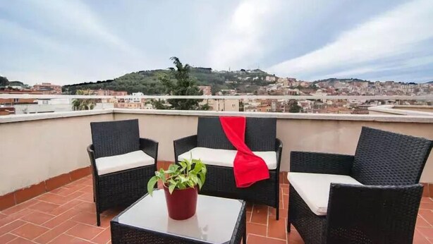 Terraço com móveis de vime, uma mesa e um vaso de planta.