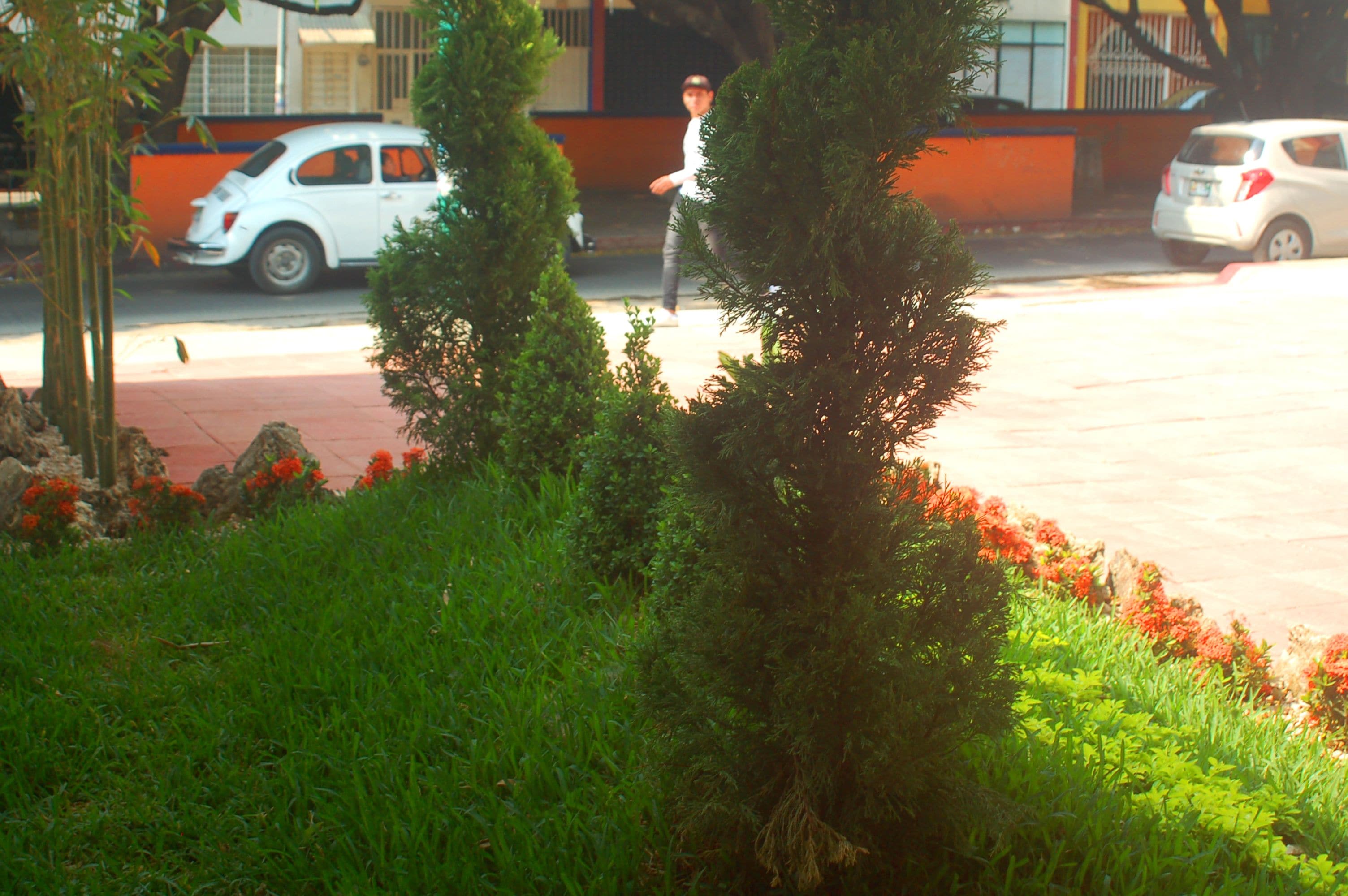 Uma área de estacionamento com um carro branco e uma pessoa caminhando.