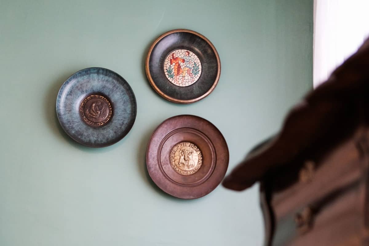 Uma área de refeições com mesa, cadeiras, um prato decorativo na parede e um aparador.