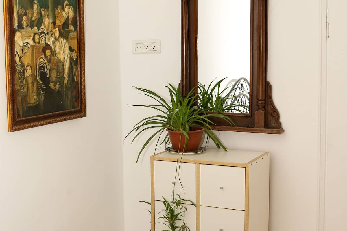 Um quarto com um armário branco, um espelho e um quadro na parede.