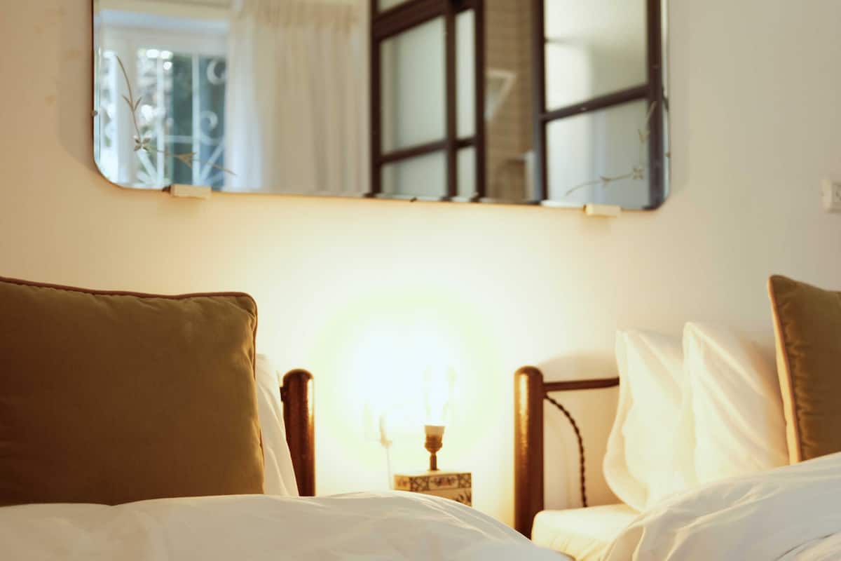 Quarto de hotel com uma cama, uma mesa de cabeceira, uma lâmpada e um espelho.
