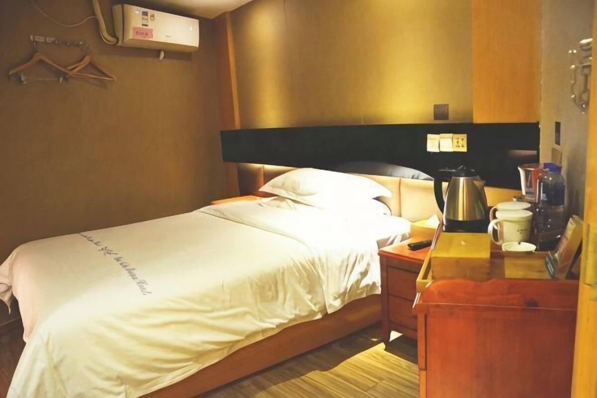 Quarto de hotel com cama, mesa de cabeceira e cafeteira.