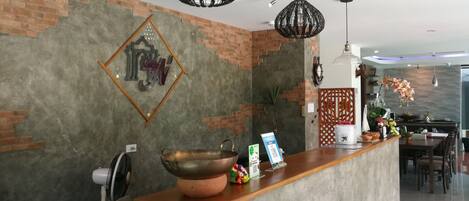 Uma área de recepção com parede de tijolos, balcão de madeira e luminárias pendentes.