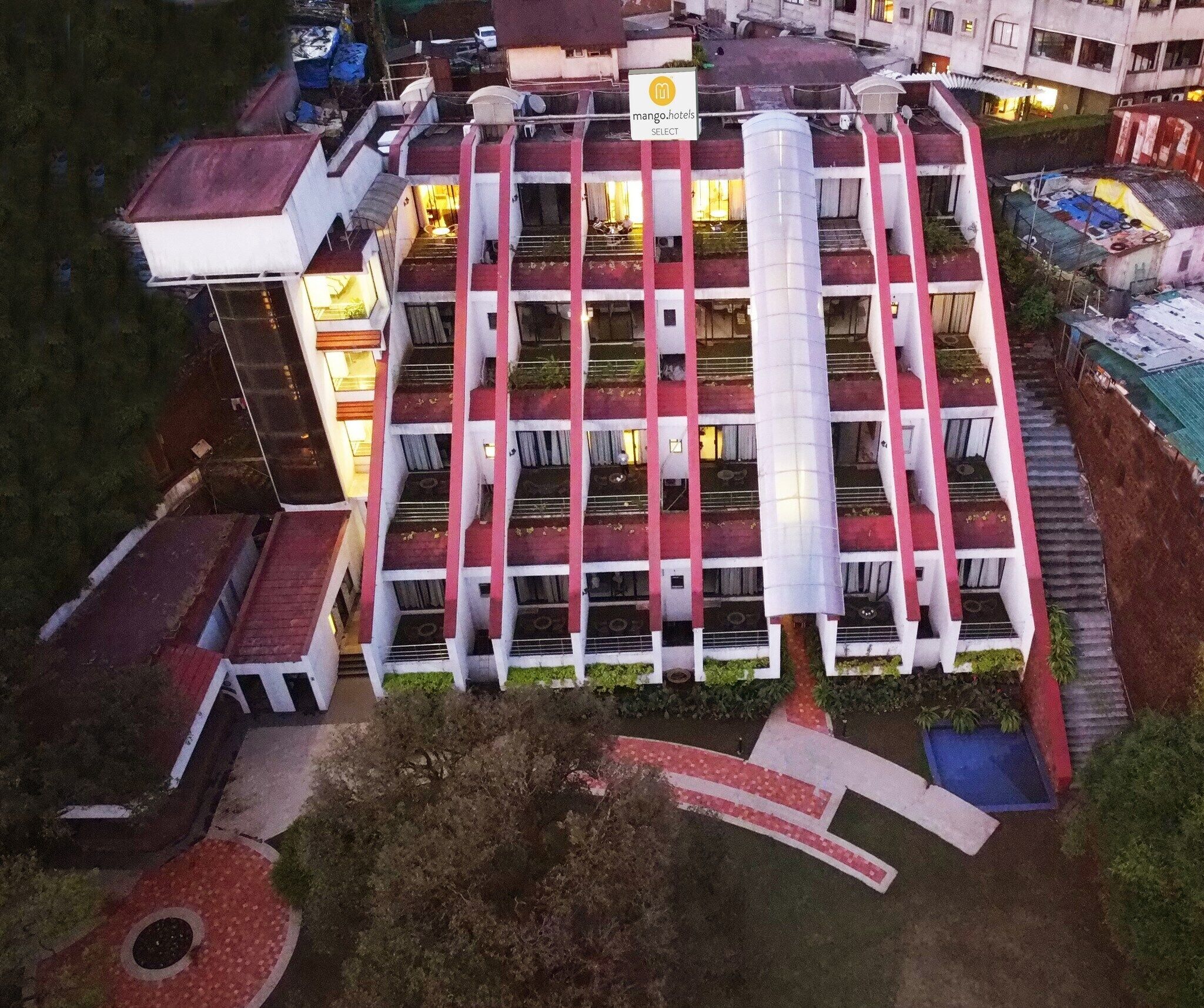 Hotel com vários andares, átrio central, varandas e terraço no telhado.