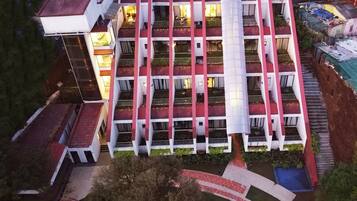 Hotel com vários andares, átrio central, varandas e terraço no telhado.
