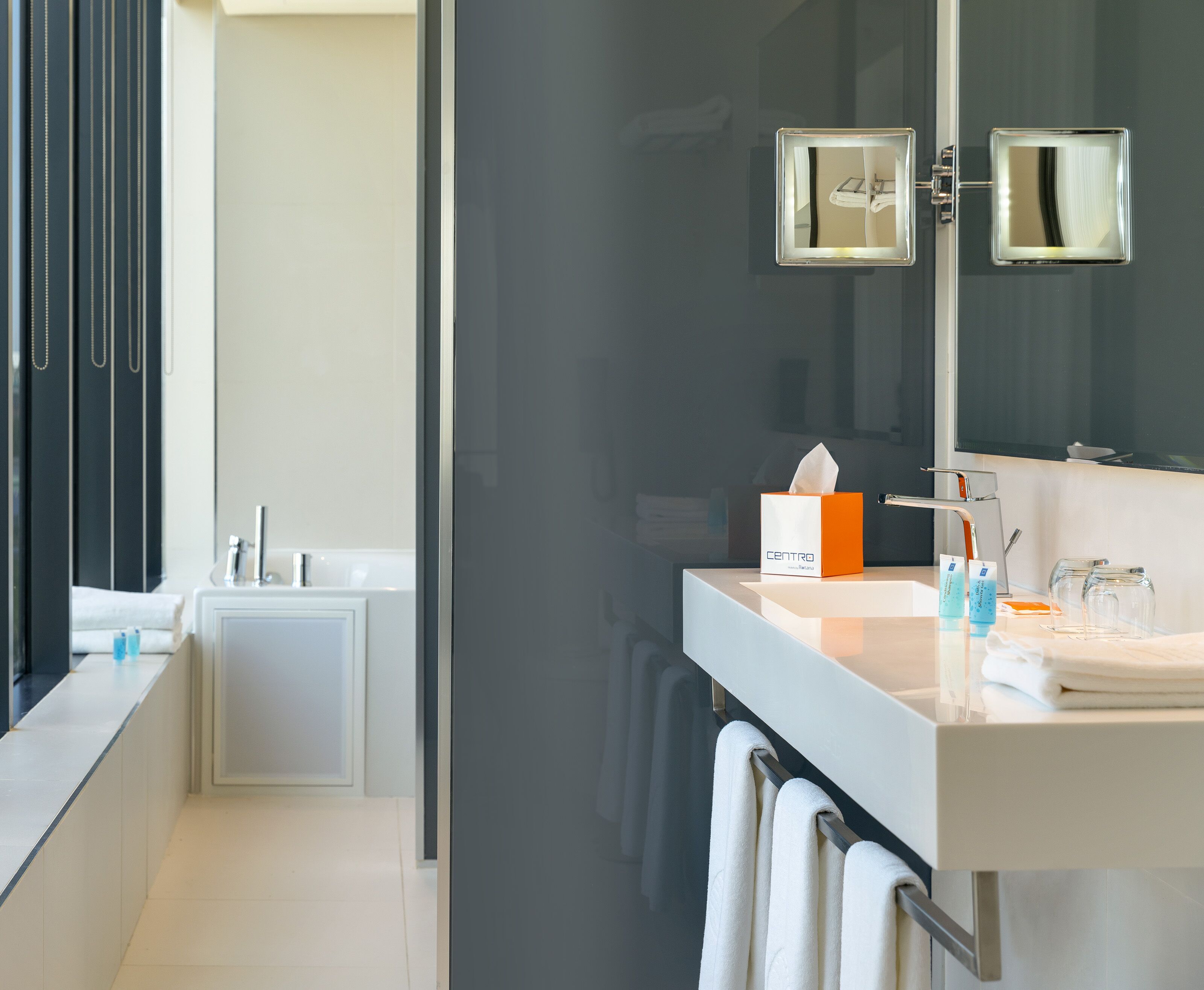Casa de banho moderna com lavatório branco, espelho e porta-toalhas.