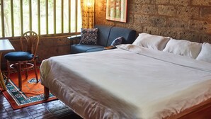 Quarto com cama, cadeira, mesa e janela com cortinas.