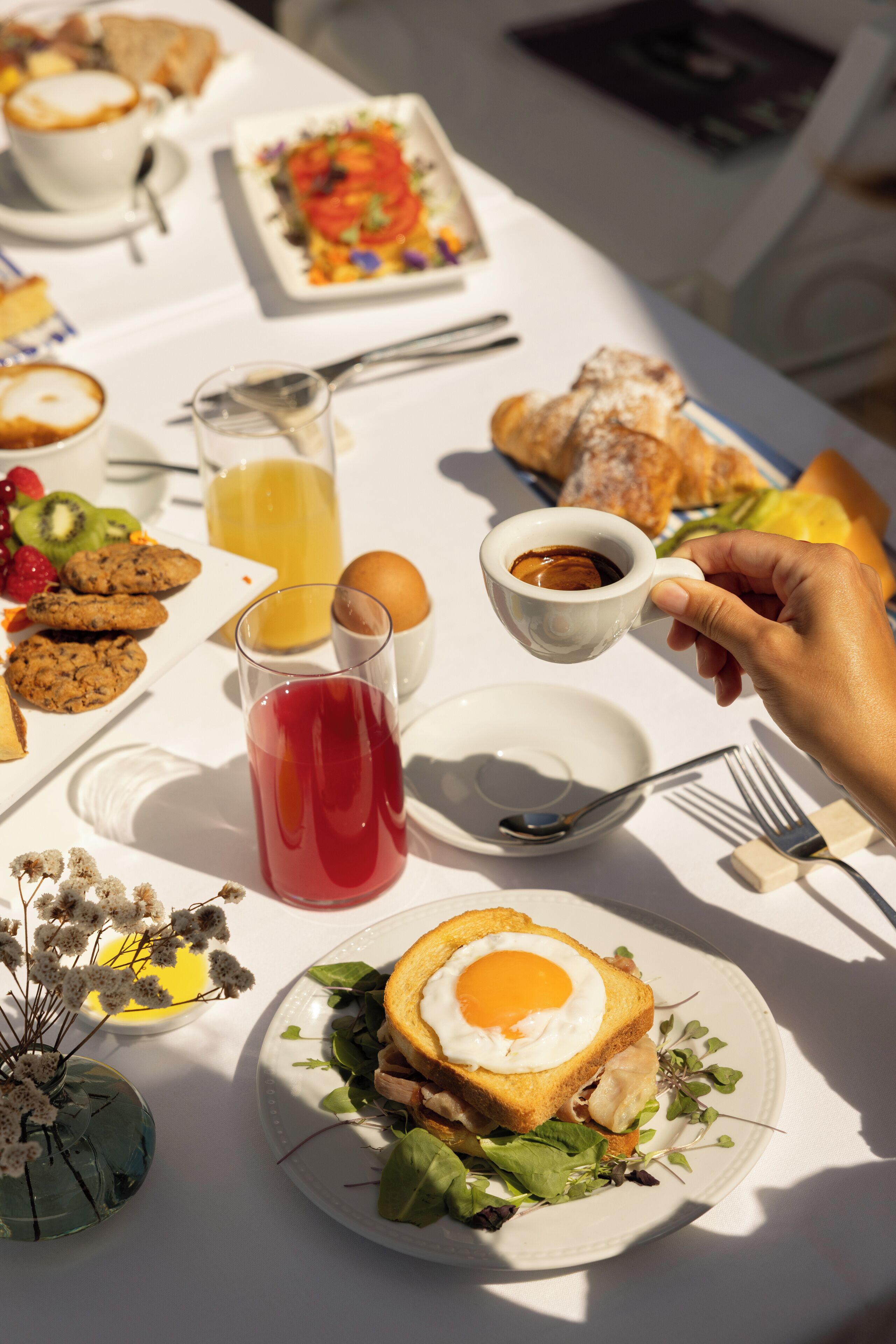 Uma mesa de café da manhã com diversos alimentos, incluindo torradas com ovo, biscoitos e um copo de suco.