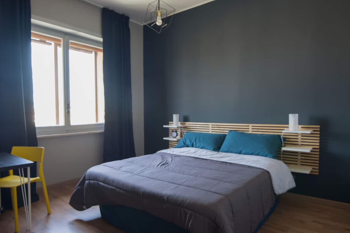 Um quarto com uma cama, uma escrivaninha e uma cadeira.