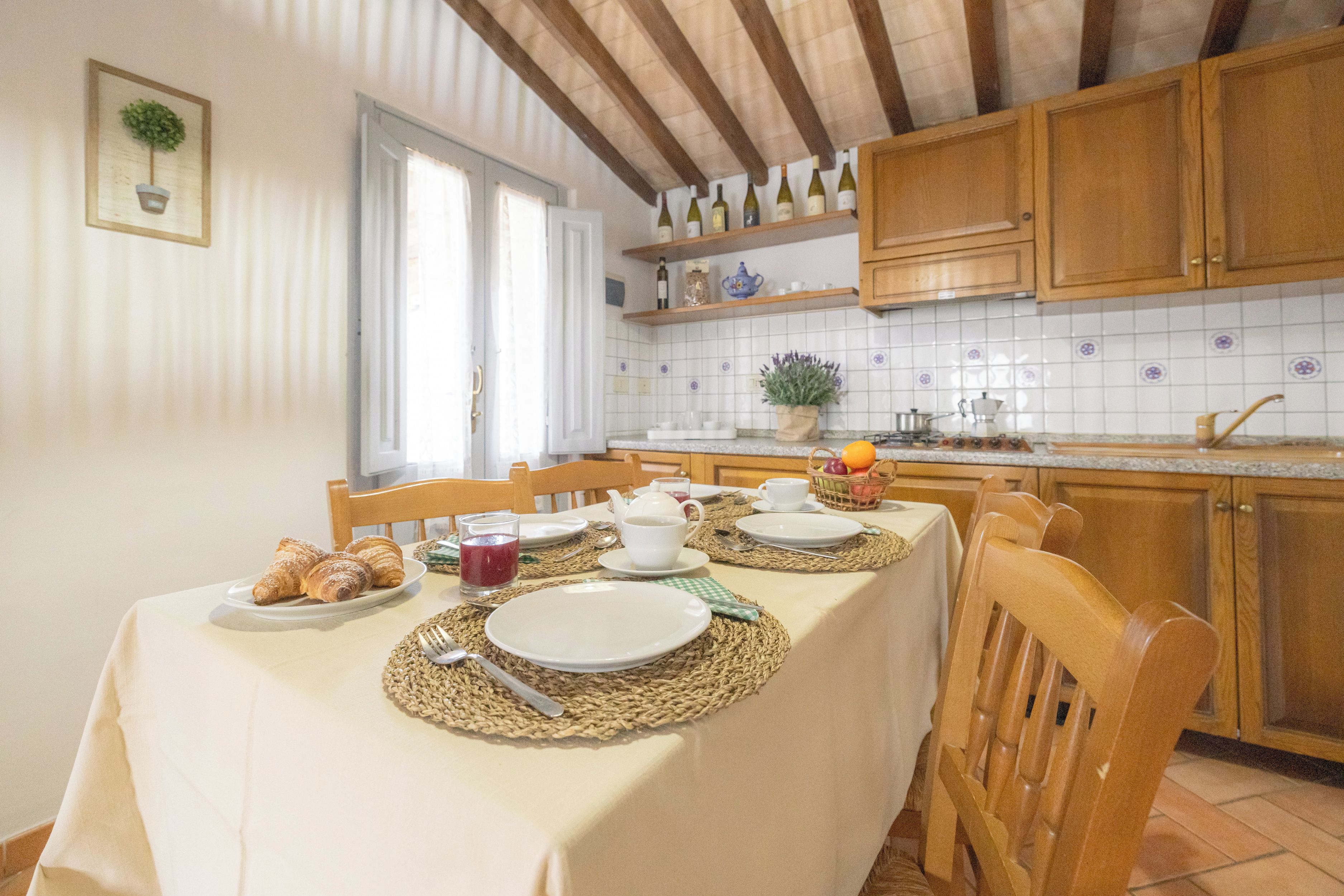 Espaço de refeições com mesa posta para o café da manhã, incluindo croissants e um copo de suco.
