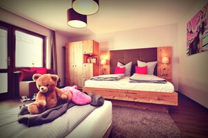 Quarto com cama de madeira, um ursinho de pelúcia e janela com cortinas.