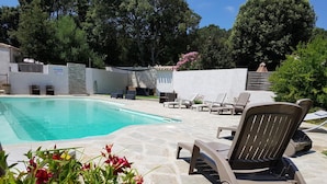 Uma piscina com espreguiçadeiras e um pátio de pedra.