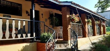 Uma casa de dois andares com varanda, escada e fachada de tijolo.