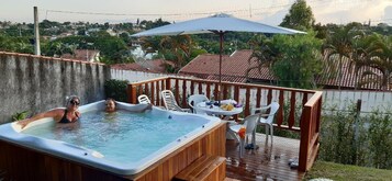 Banheira de hidromassagem em deck de madeira com vista para uma área residencial.