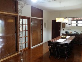 Quarto japonês tradicional com portas de correr, mesa de madeira para refeições e luminária pendente.
