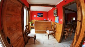 Quarto com mobiliário de madeira, balcão de recepção e parede vermelha.