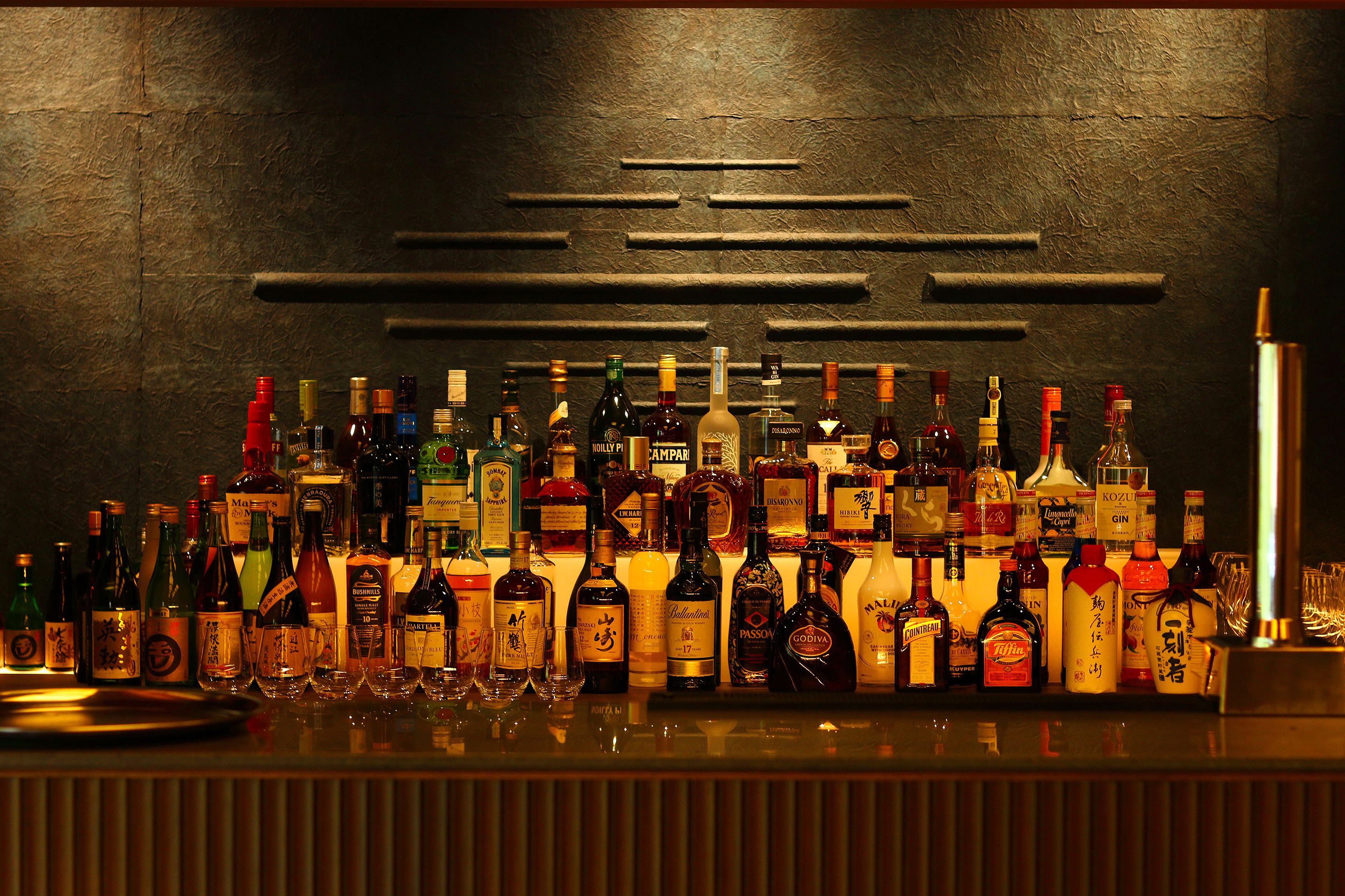 Um bar com várias garrafas de álcool e copos.