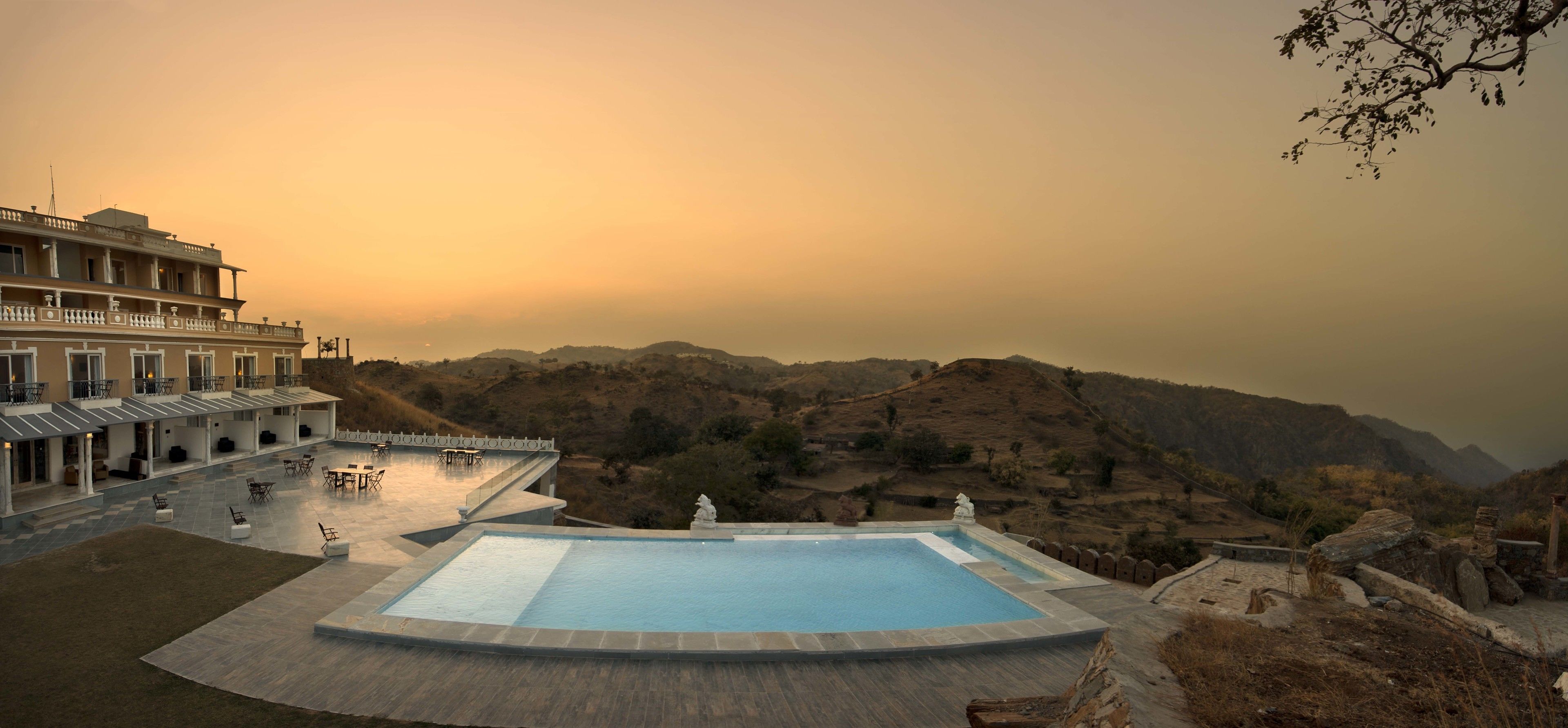 Hotel com piscina, área de estar ao ar livre e vista para as colinas ao redor.