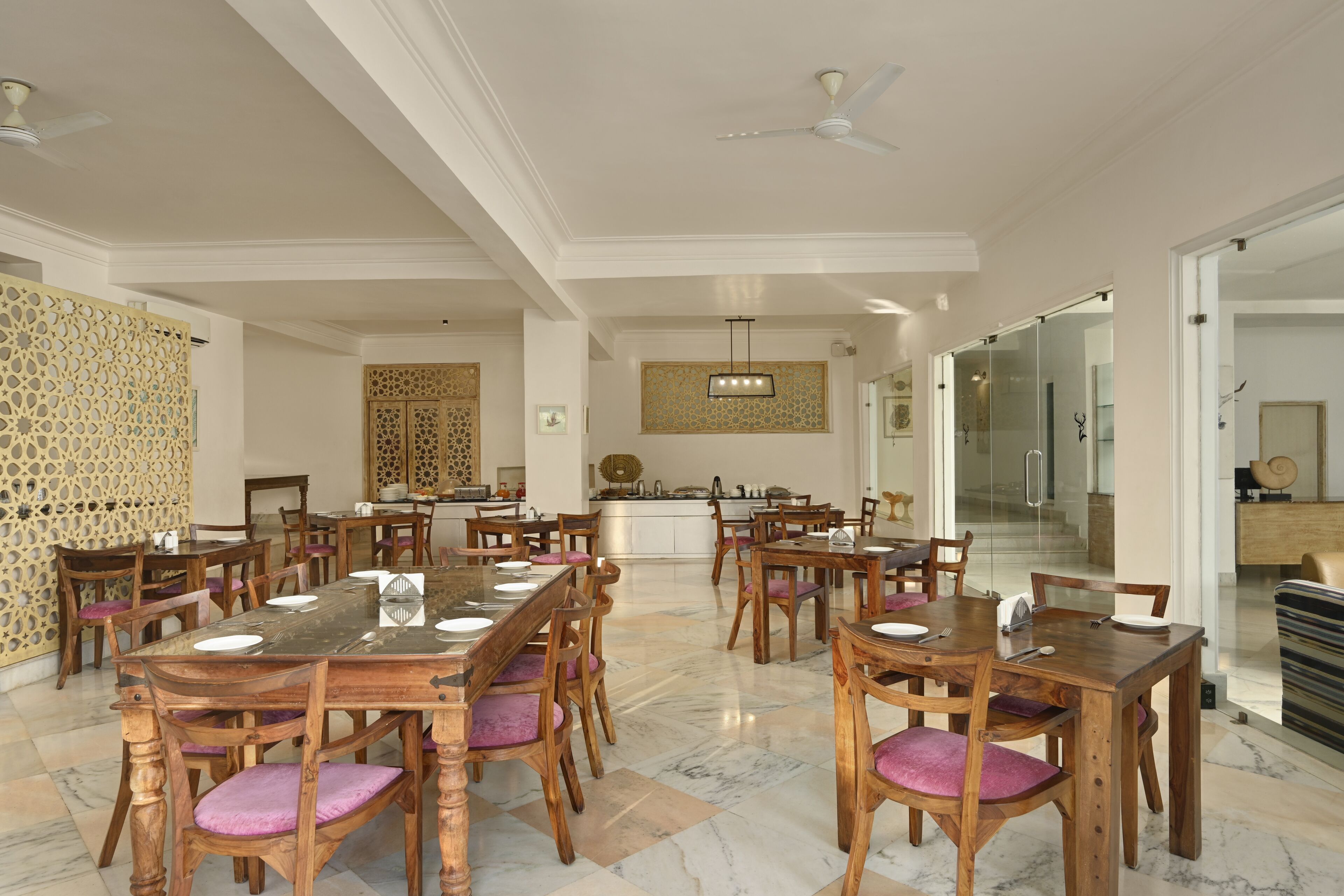 Uma sala de jantar espaçosa com mesas e cadeiras de madeira, uma ilha central e uma parede decorativa.