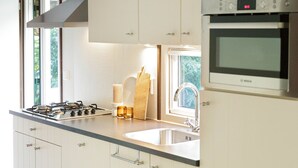 Cozinha moderna com armários brancos, fogão de aço inoxidável e forno Bosch.