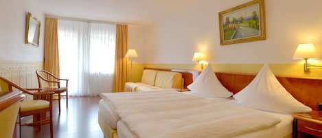 Quarto de hotel com duas camas, uma escrivaninha, uma cadeira e um quadro na parede.