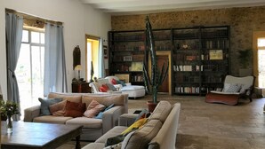 Uma sala de estar ampla com uma grande estante de livros, um sofá confortável e uma planta de cacto.