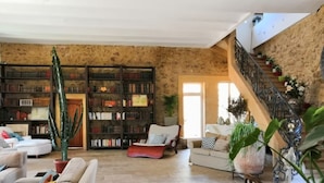 Uma sala de estar espaçosa com uma grande estante, um sofá confortável e uma escada que dá para um andar superior.