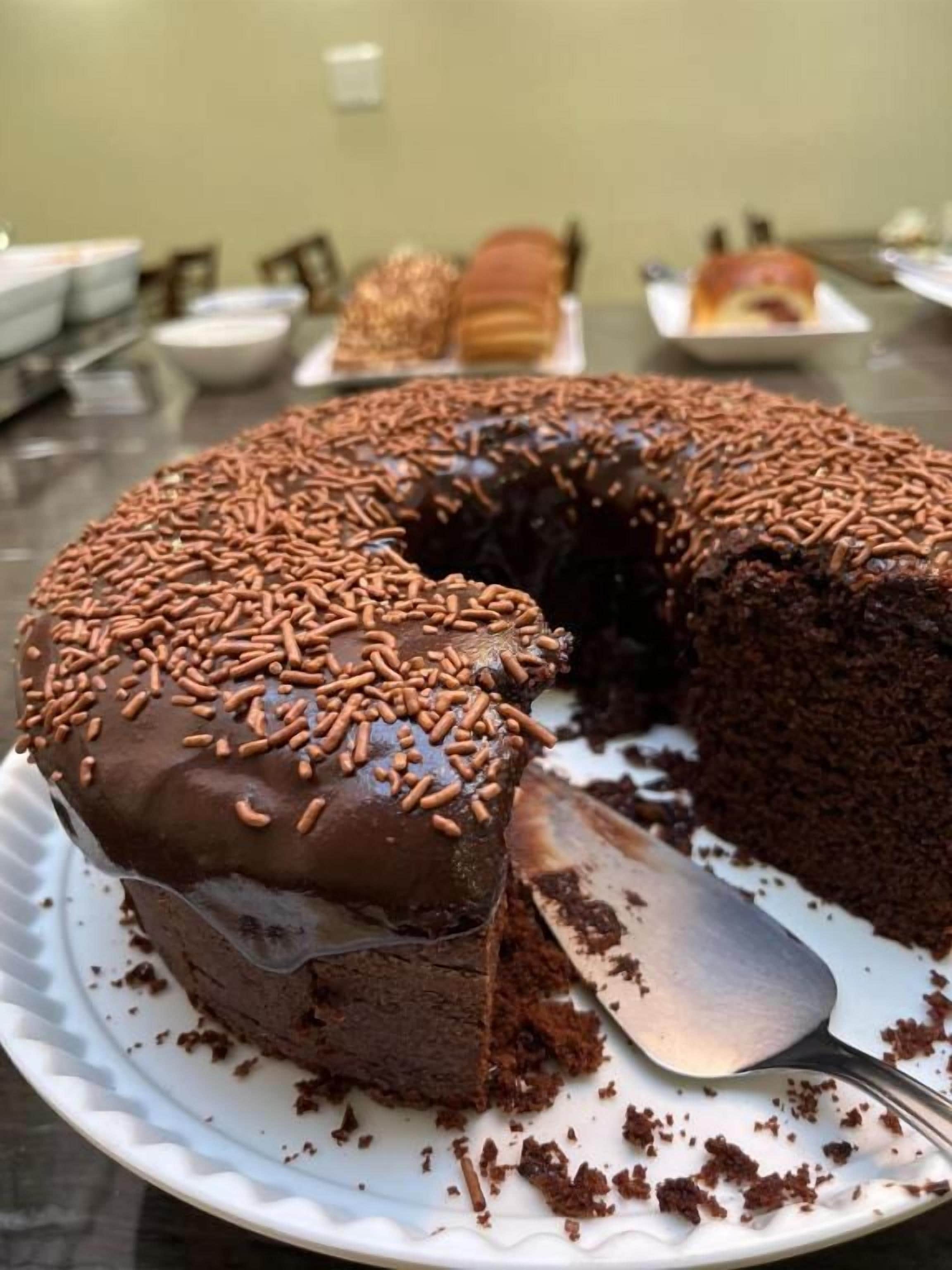 Um bolo de chocolate com granulado sobre um prato branco.