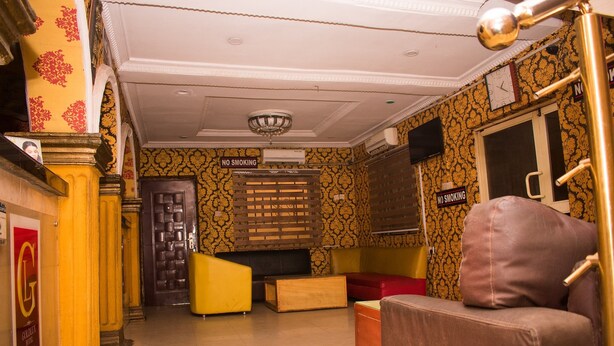 Um hall com placa de 'Proibido Fumar', um relógio e um candelabro.