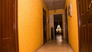 Corredor com paredes amarelas e portas de madeira.