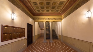 Um corredor com piso estampado, área de armários de madeira e uma escada.
