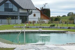 Uma casa moderna com piscina, cercada por um jardim bem cuidado e um cercado de madeira.