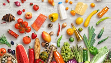 Diversas frutas frescas, legumes e produtos lácteos dispostos sobre uma superfície de madeira.