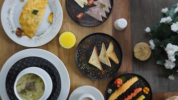 Disposição para o pequeno-almoço com pratos de comida, incluindo um omelete, torradas e sopa.